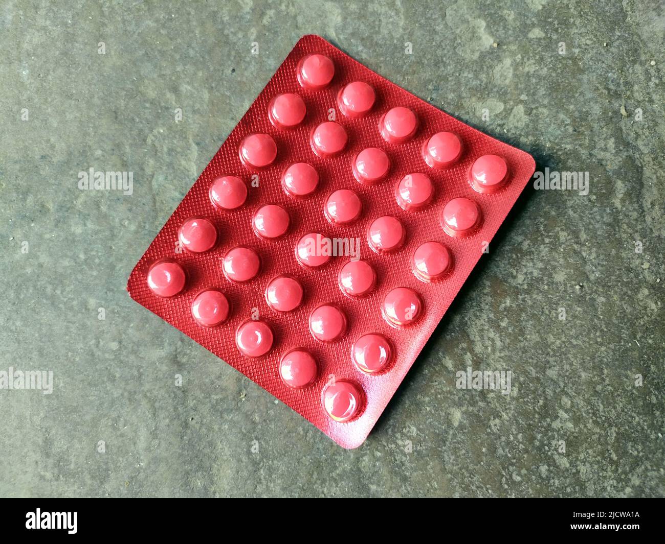 red color medicin pill isolated on stone background Stock Photo - Alamy
