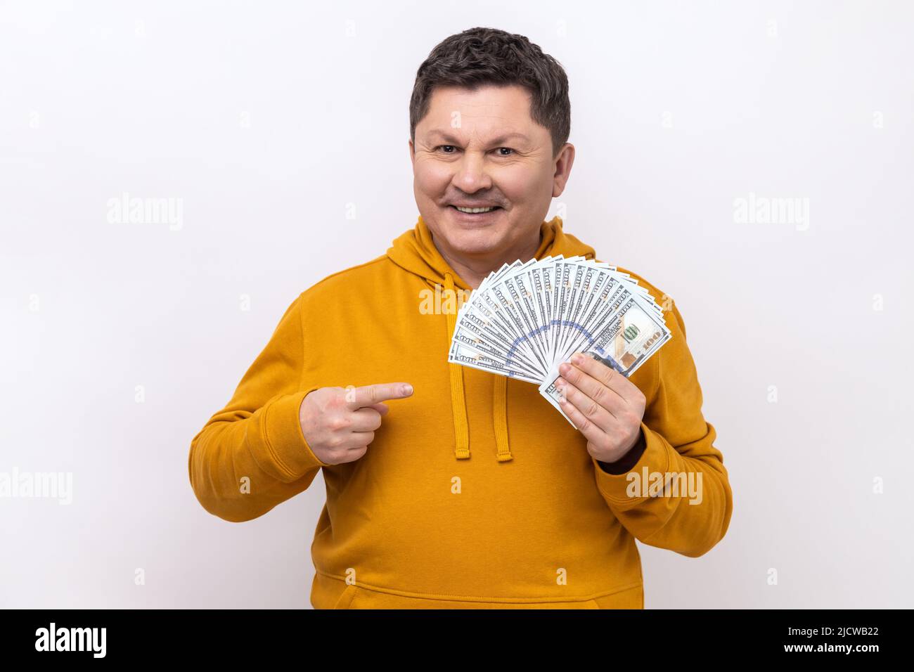 Smiling rich man pointing at big fan of dollars banknotes with finger ...