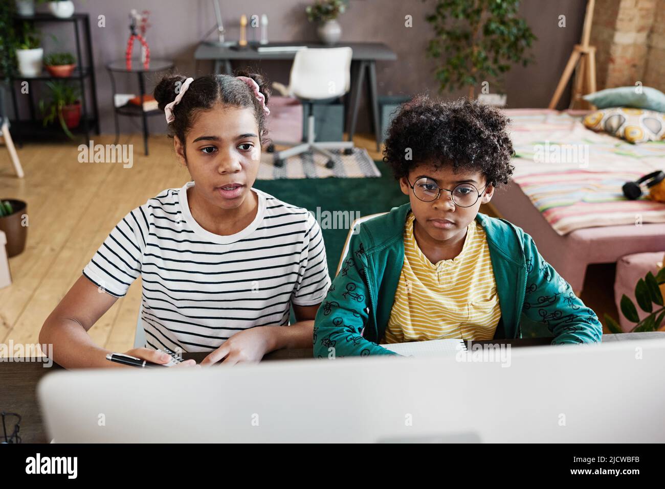 Two African school children sitting at table in front of computer ...