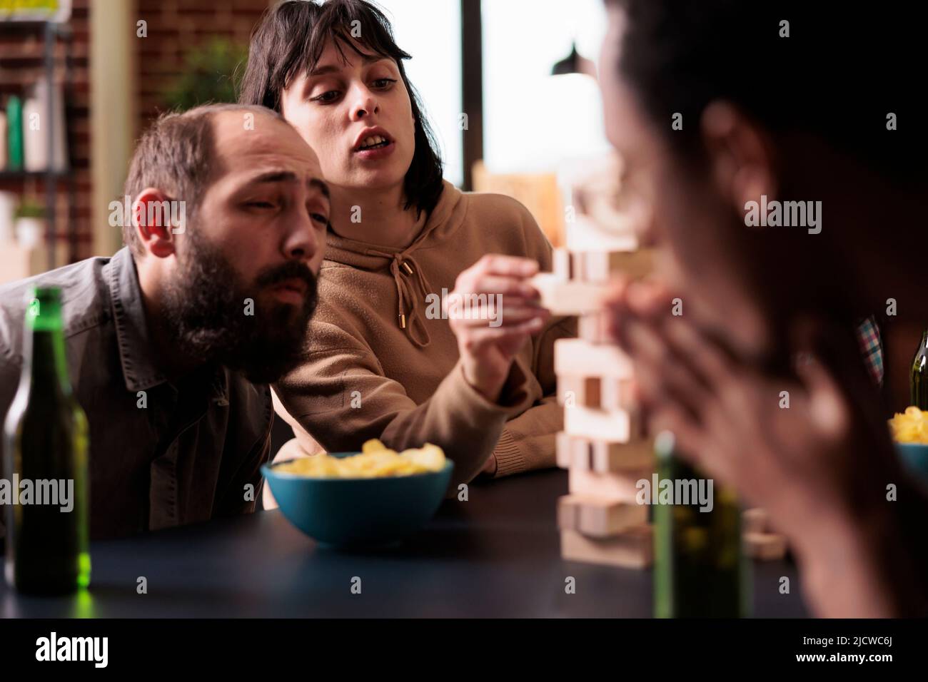 Concentrated woman carefully removing wooden block from wood tower ...
