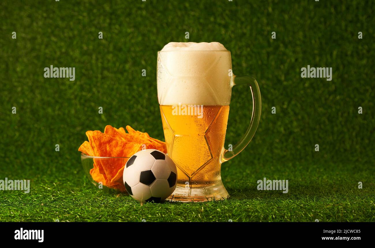 Glass of beer with soccer ball on the green grass background. Football ...