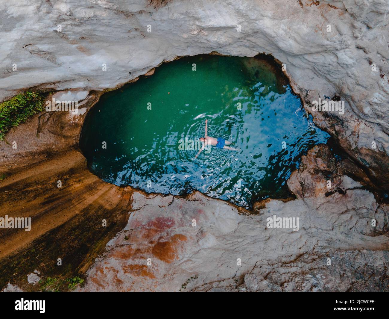 overhead view of dimosari waterfall lake with happy man floating on the ...