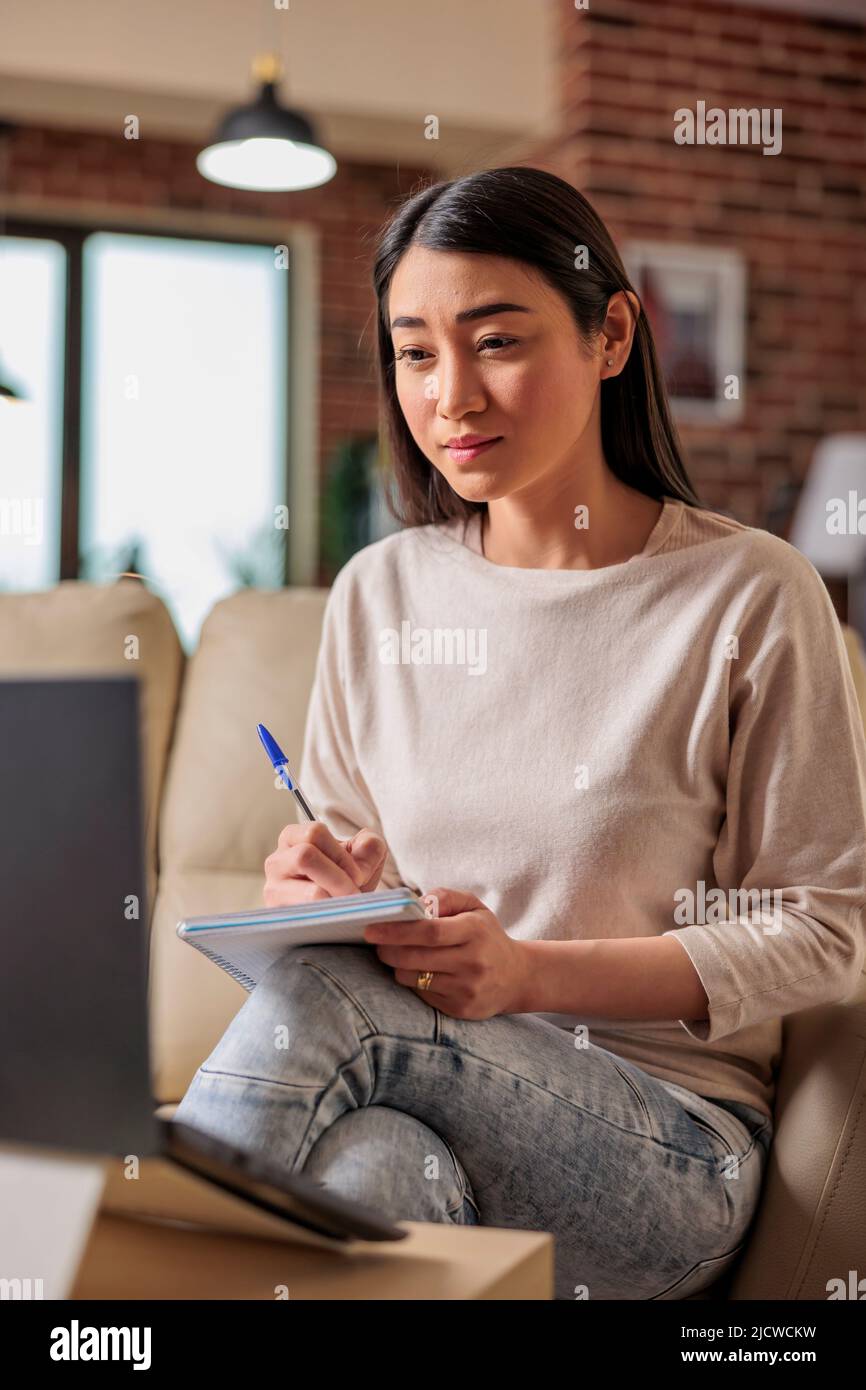 Asian woman taking notes in distance e learning online training classes ...