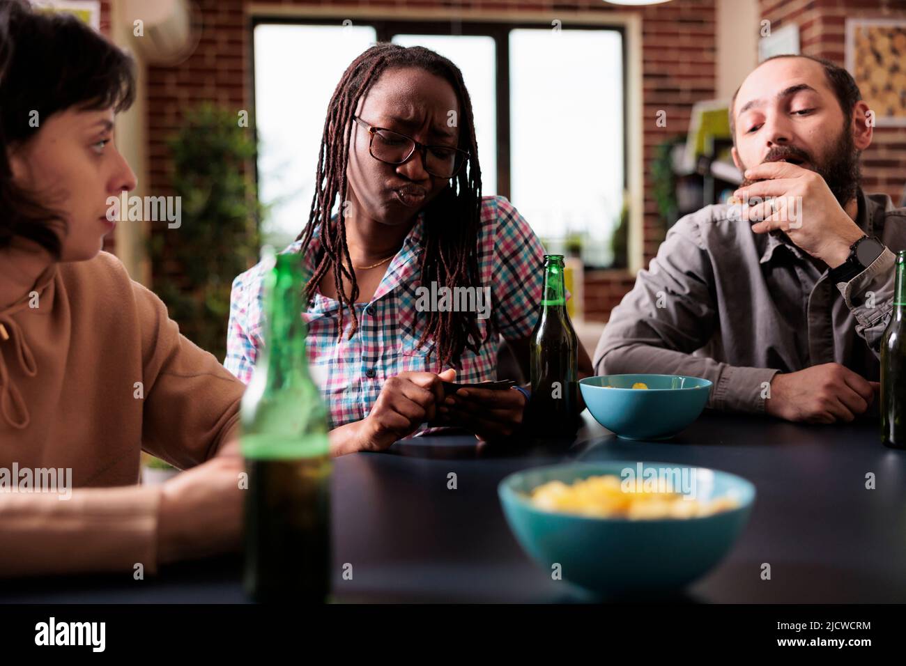 Casual multiethnic friends playing card games together while enjoying ...