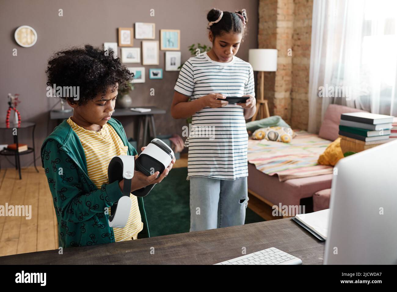 Children using modern gadgets to play virtual game in the room during ...