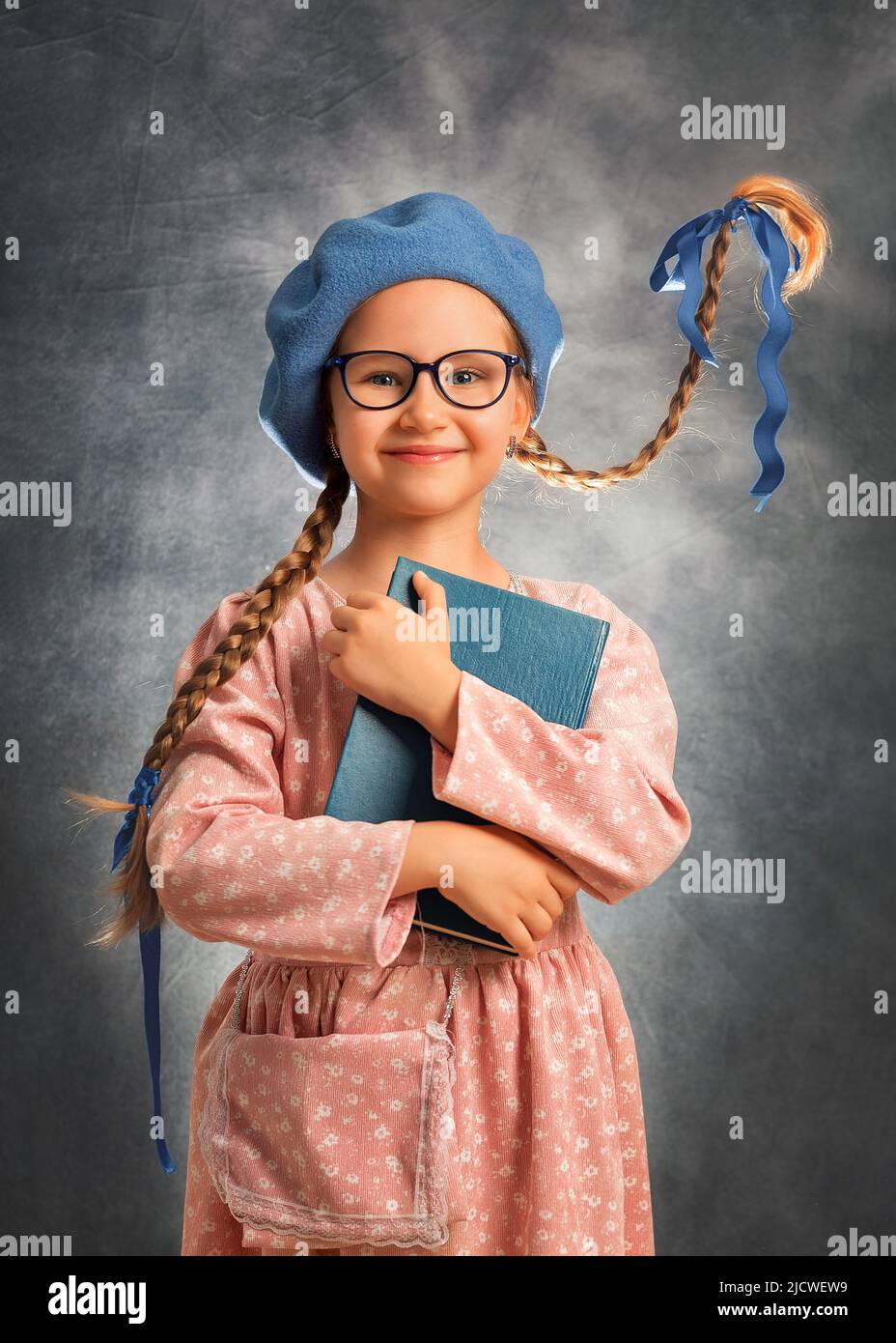 Close portrait of a happy girl kid with two flying braids on a gray ...