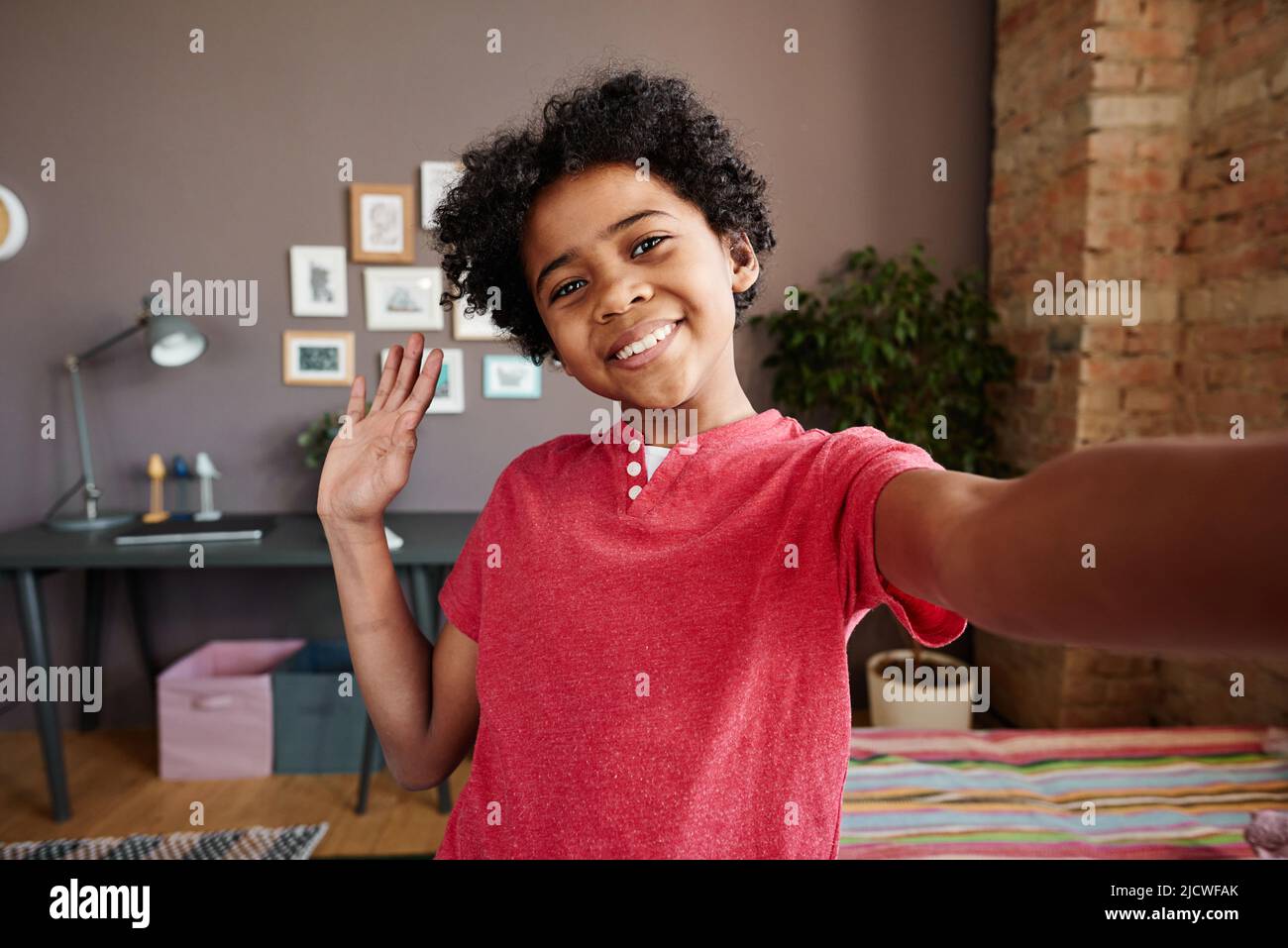 African happy kid waving his hand and smiling during video call on his ...