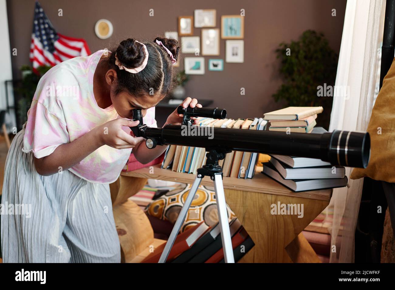 African girl exploring stars and space with telescope in her room, she ...