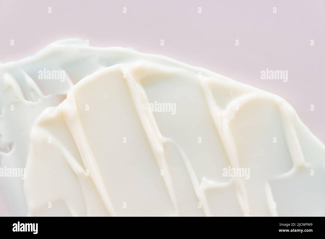 White cream texture on a pastel background. White cream swatch with ...