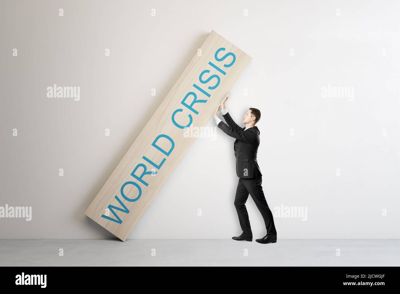 World crisis concept with man in black suit trying to push heavy wooden ...