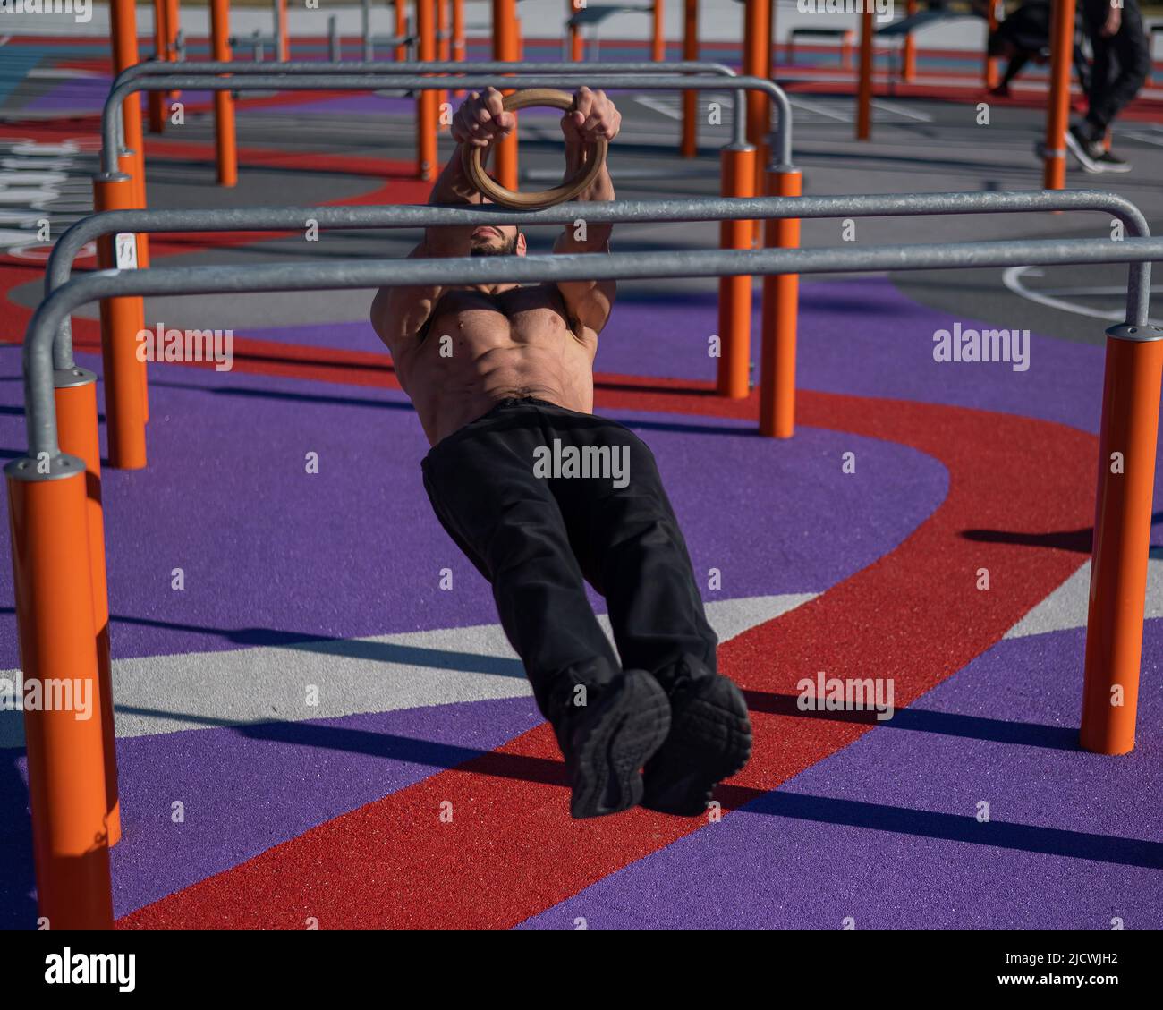 Shirtless man doing horizontal balance on parallel bars at sports ...
