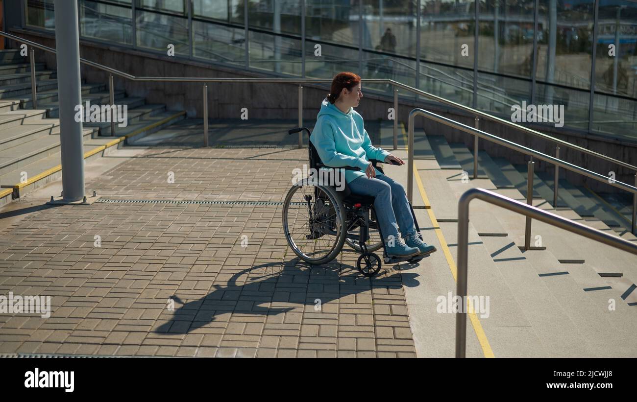 A caucasian woman in a wheelchair cannot go down stairs without a ramp ...