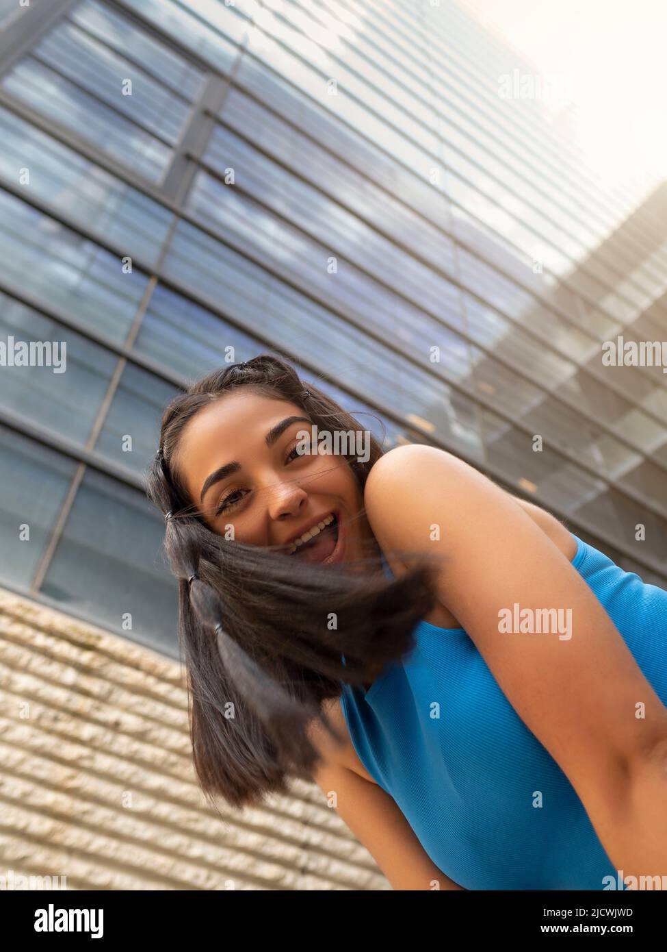 From below cheerful young Hispanic brunette bending forward and looking ...