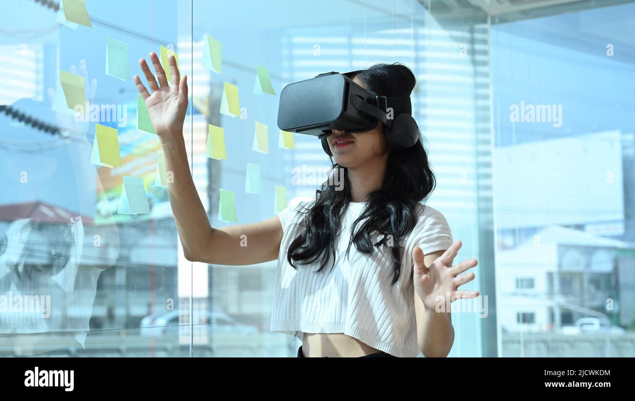 Young female developer wearing virtual reality glasses, interacting ...