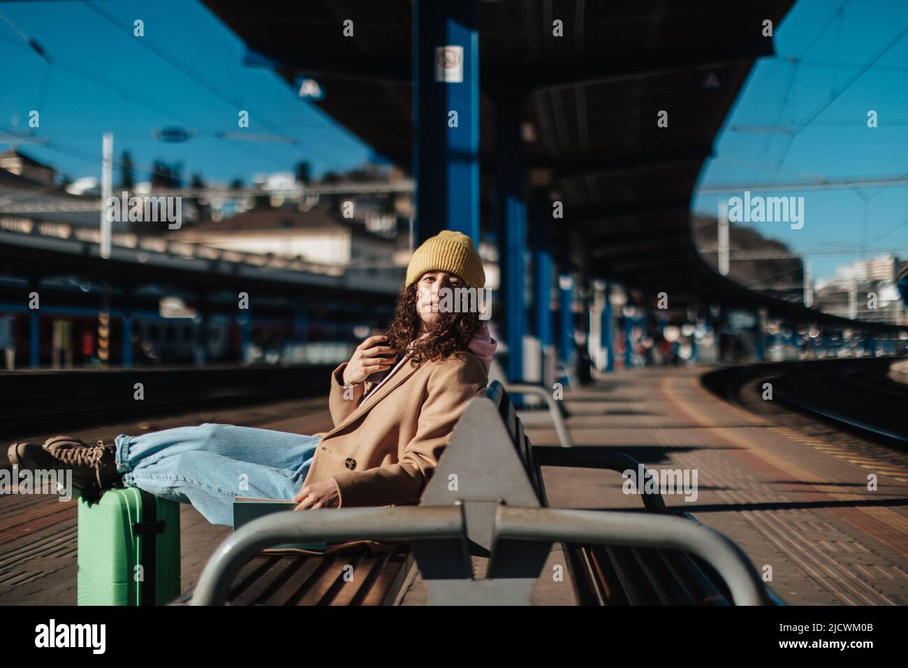 Young traveler woman sitting alone at train station platform with ...