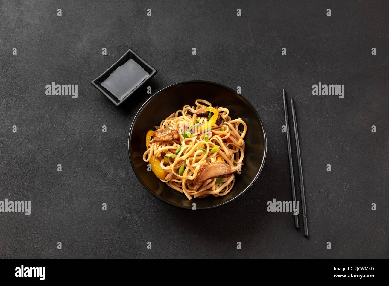 Udon noodles in a black plate on a dark background. Asian cuisine Stock ...