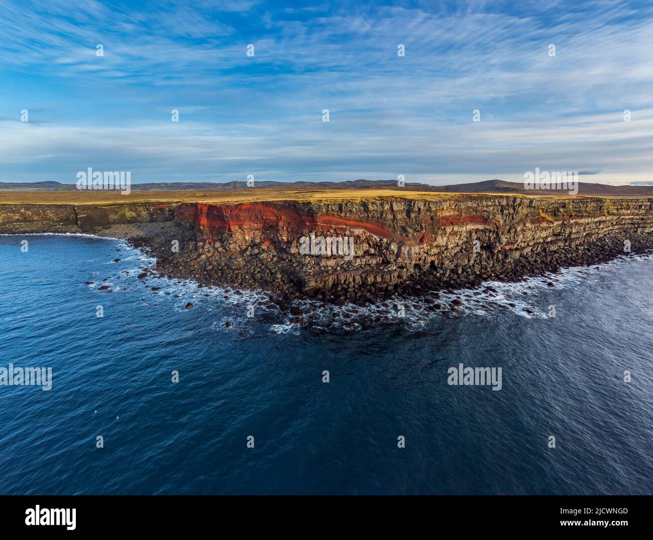 Steep cliffs with red seams in Iceland, oceans view Stock Photo - Alamy