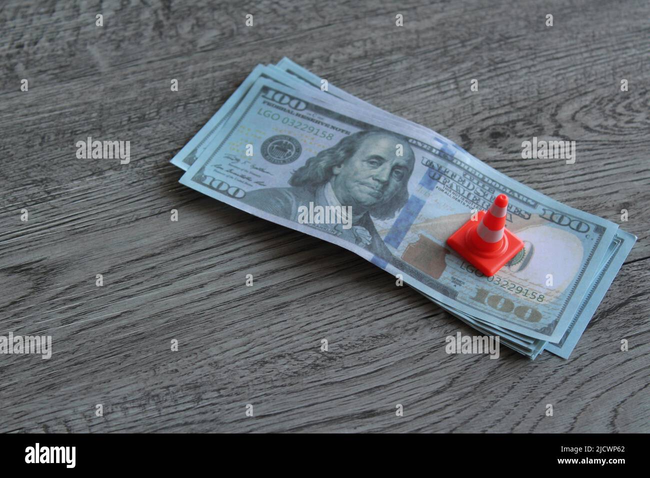 Safety cone on top of money. Revise investment, money saving plan ...