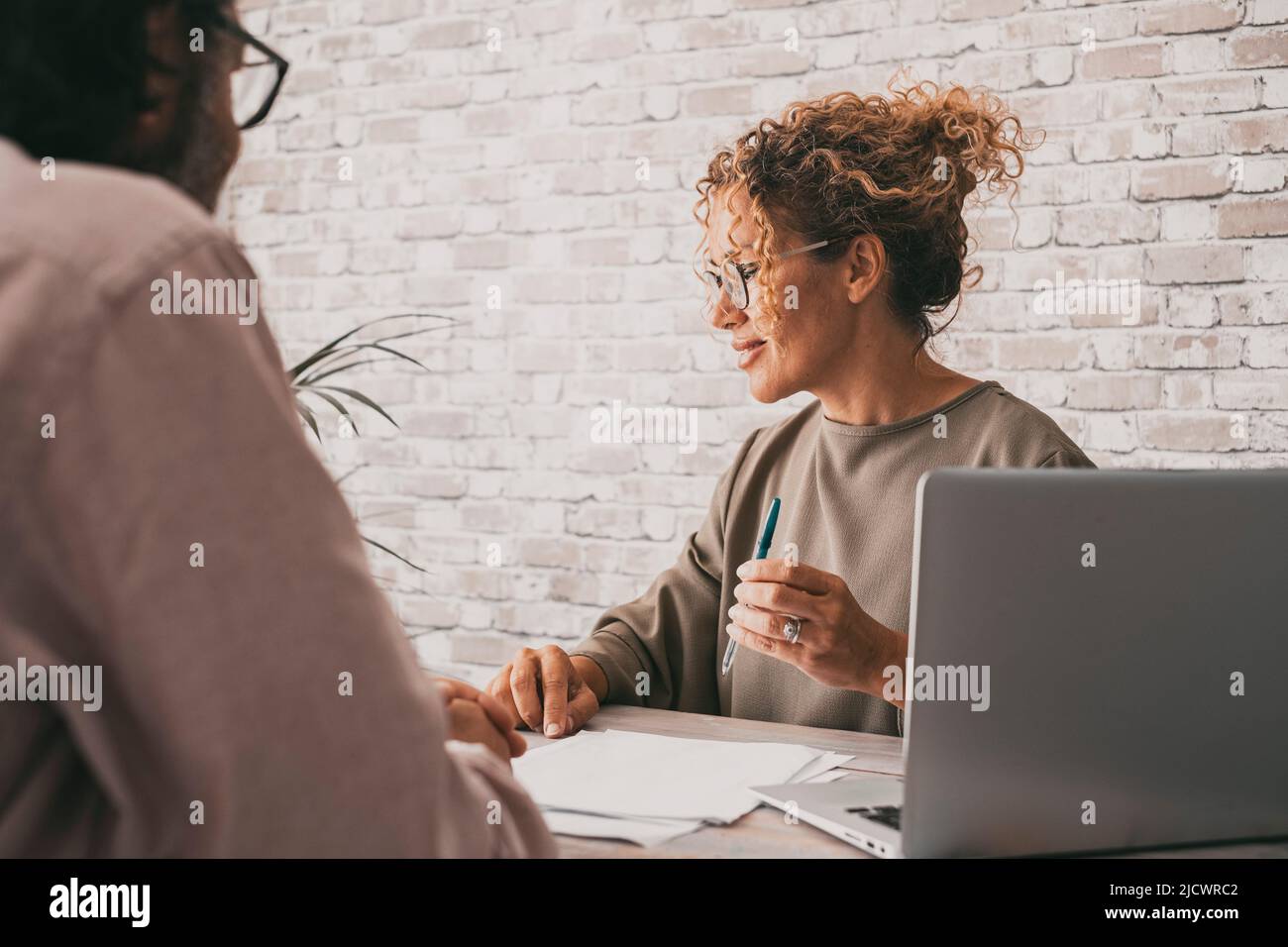 Woman at the office desk smile and work with client. Back view of man ...