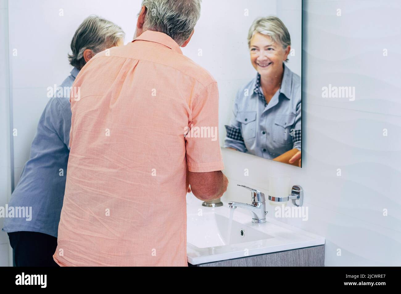 Senior age caucasian couple in the bathroom at home washing hands ...