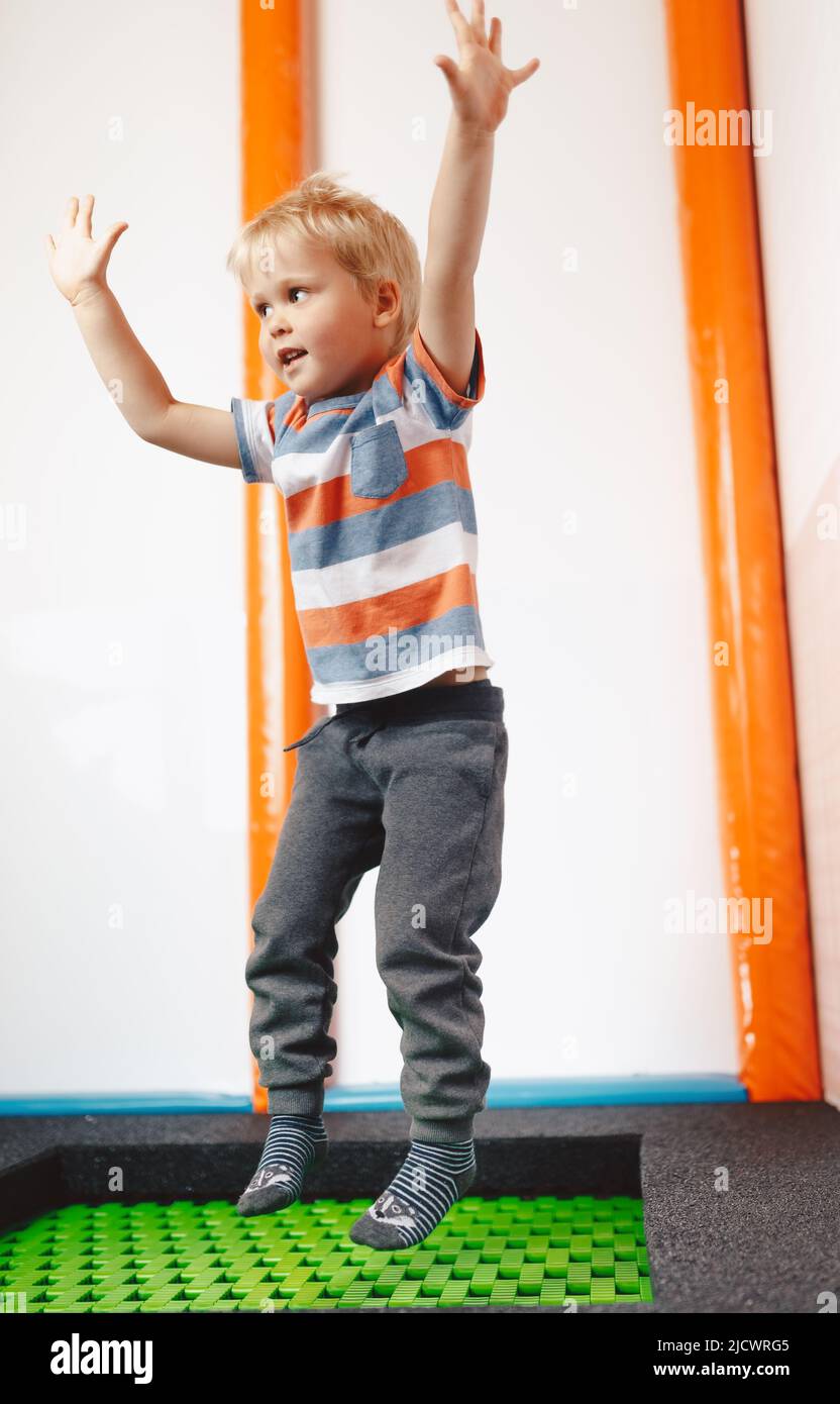 Happy school boy jumping on a trampoline in an amusement park. Kid ...