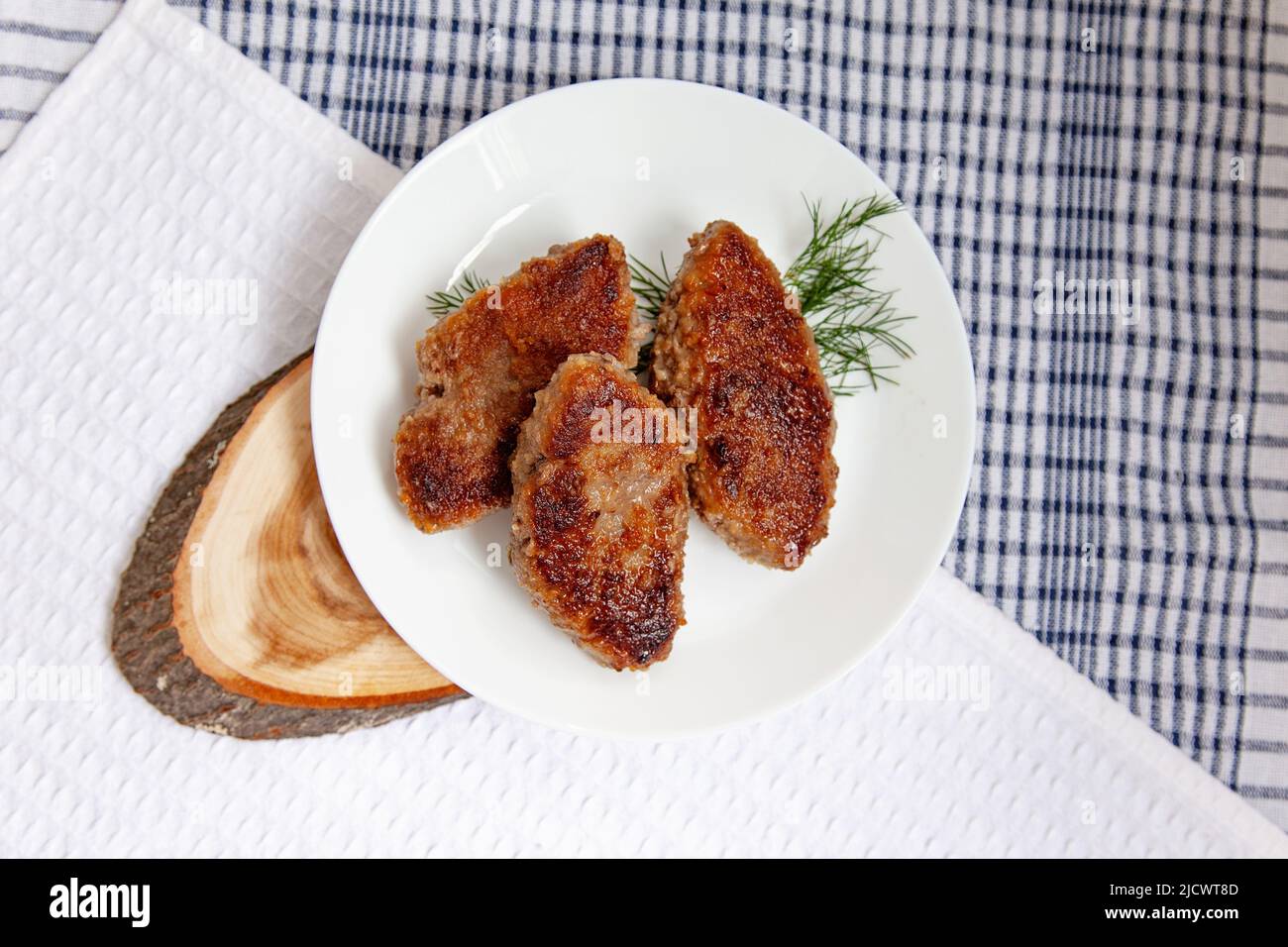 White plate with beef cutlets laying on traditional cheched kitchen ...