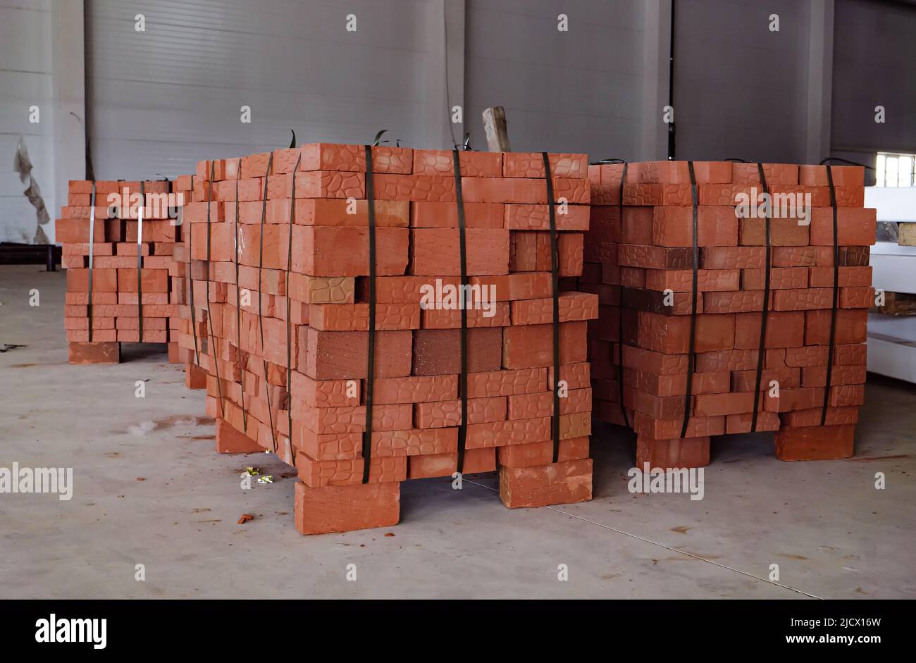 Red building bricks stacked on an outdoor warehouse. Material delivered ...