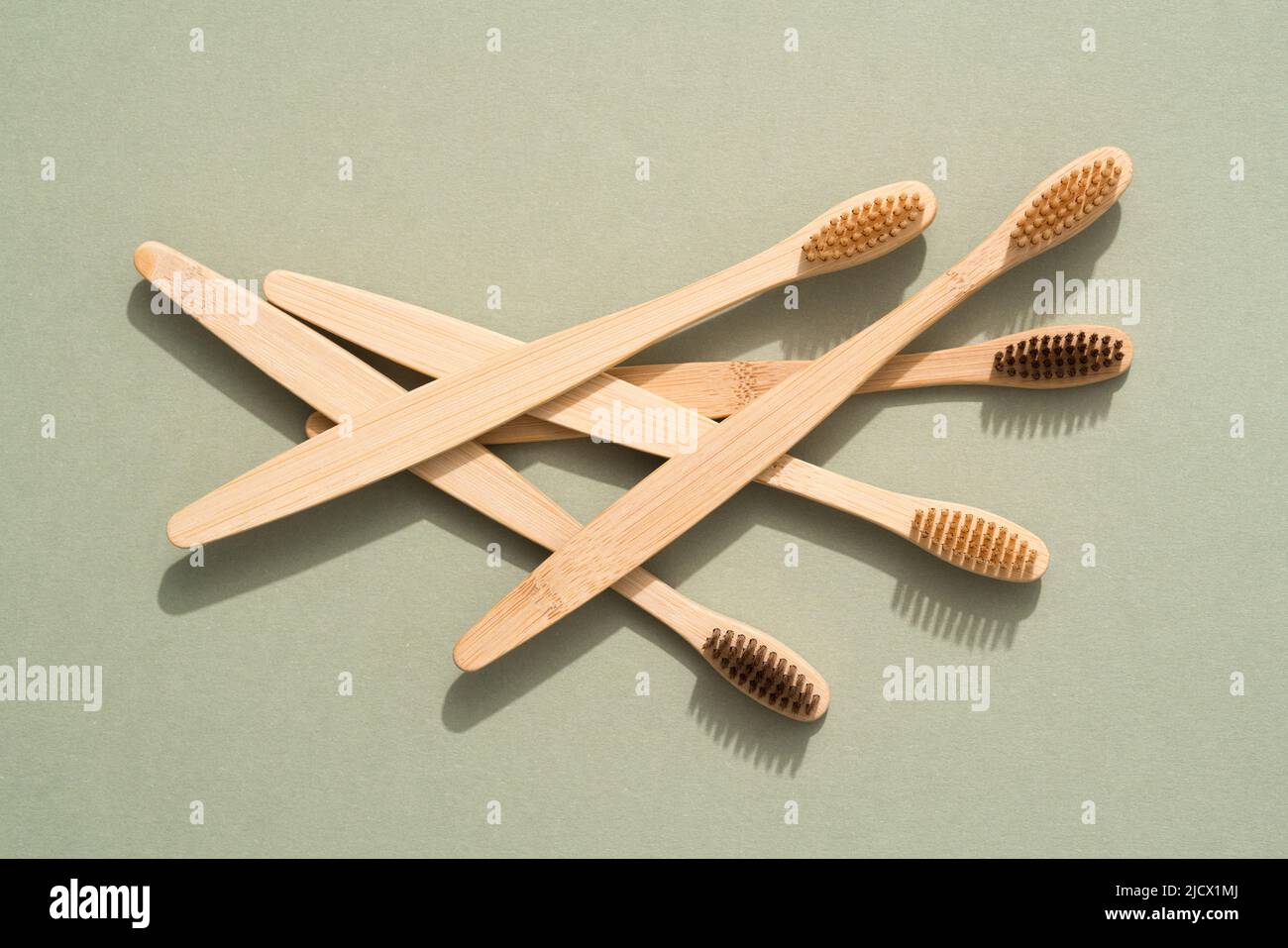 Several natural wooden toothbrushes over olive green background ...
