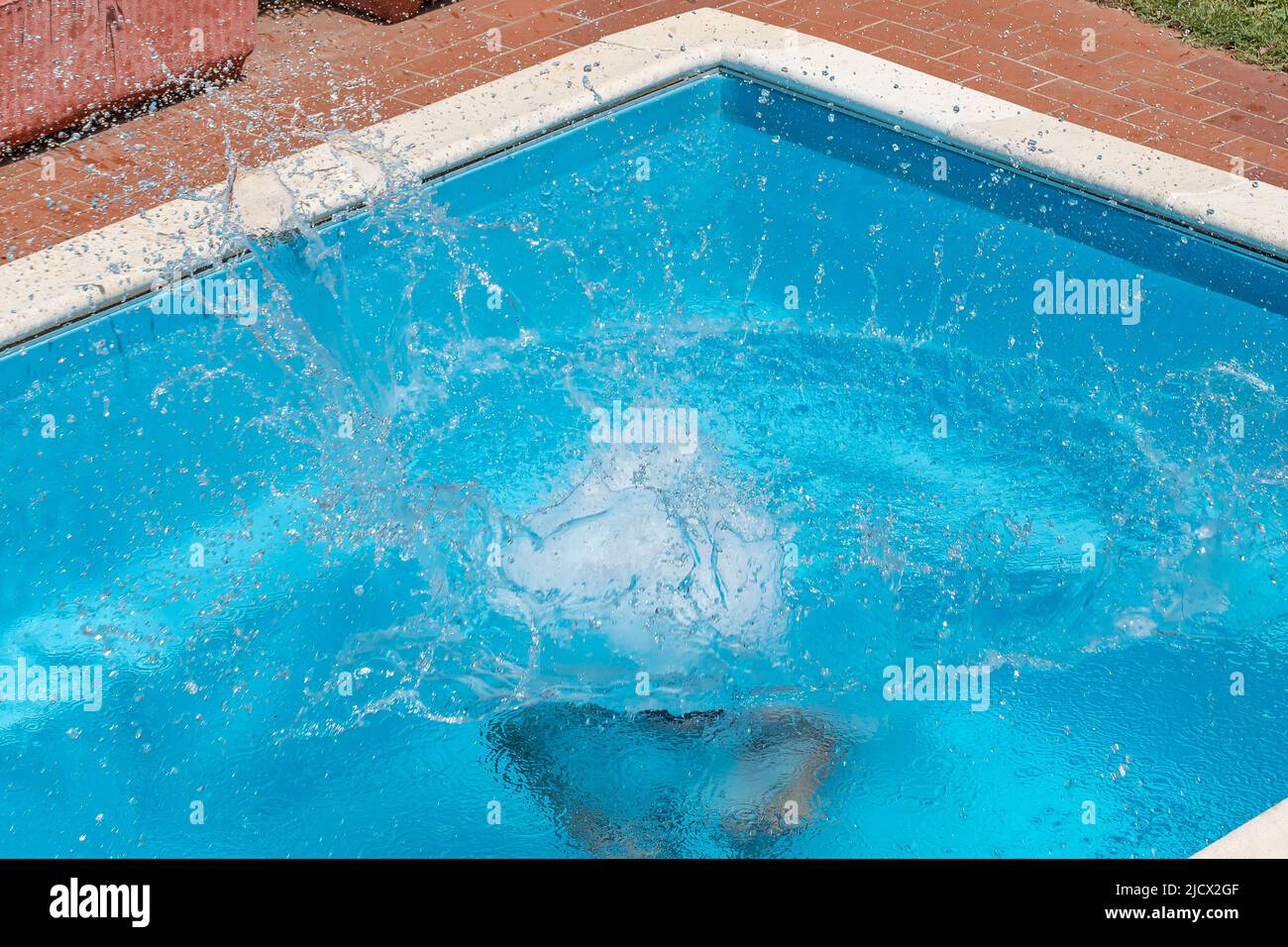 A huge splash of water is created by a cannonball dive into a swimming ...