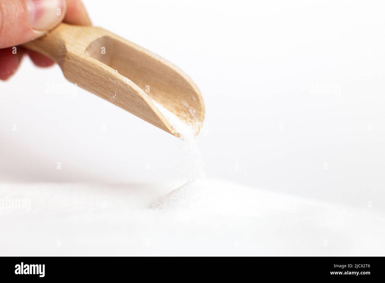 hand with a wooden spoon of salt grain on a white background Stock ...