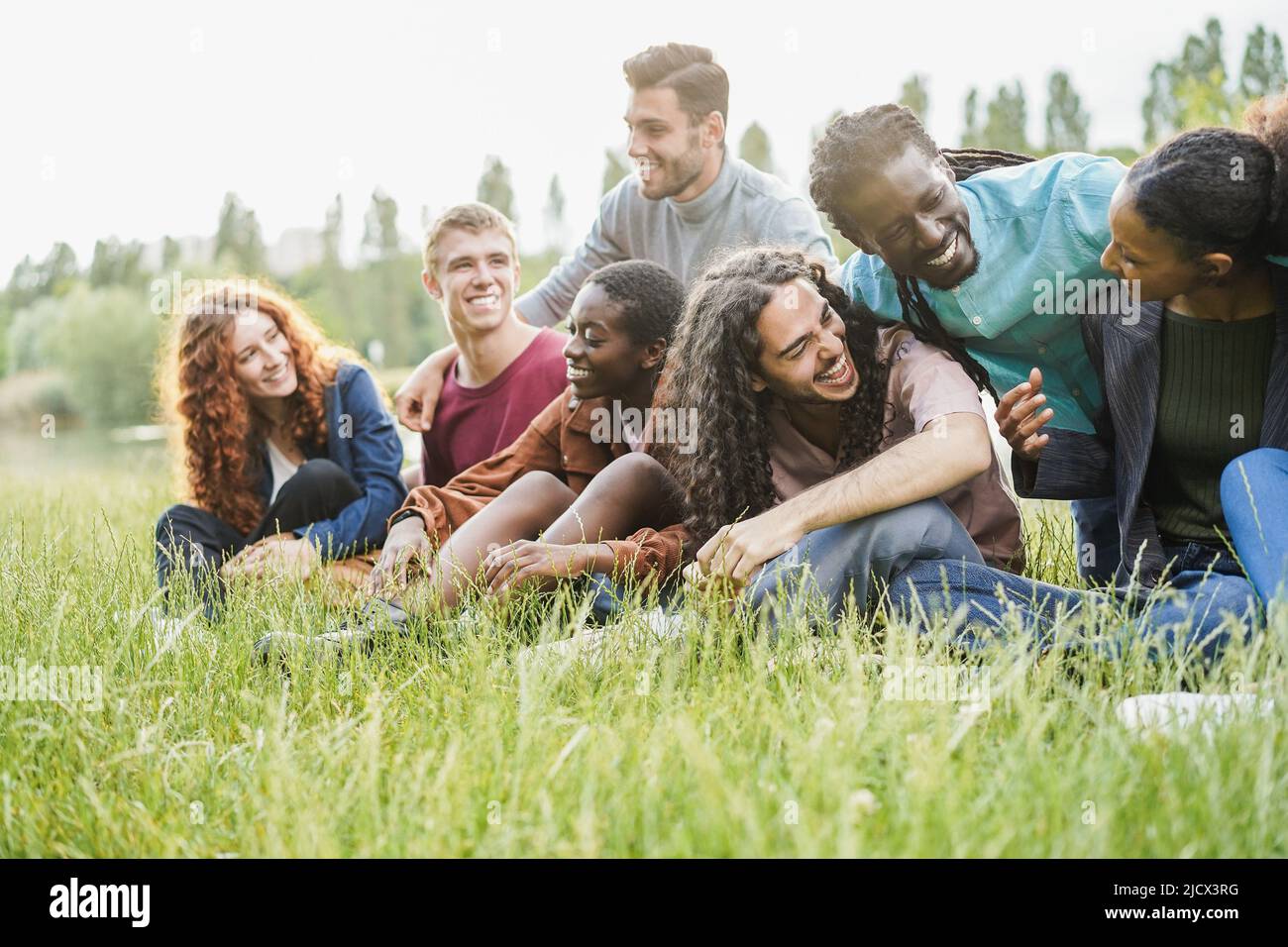 Multiracial happy people having fun sitting on grass outdoor - Soft ...