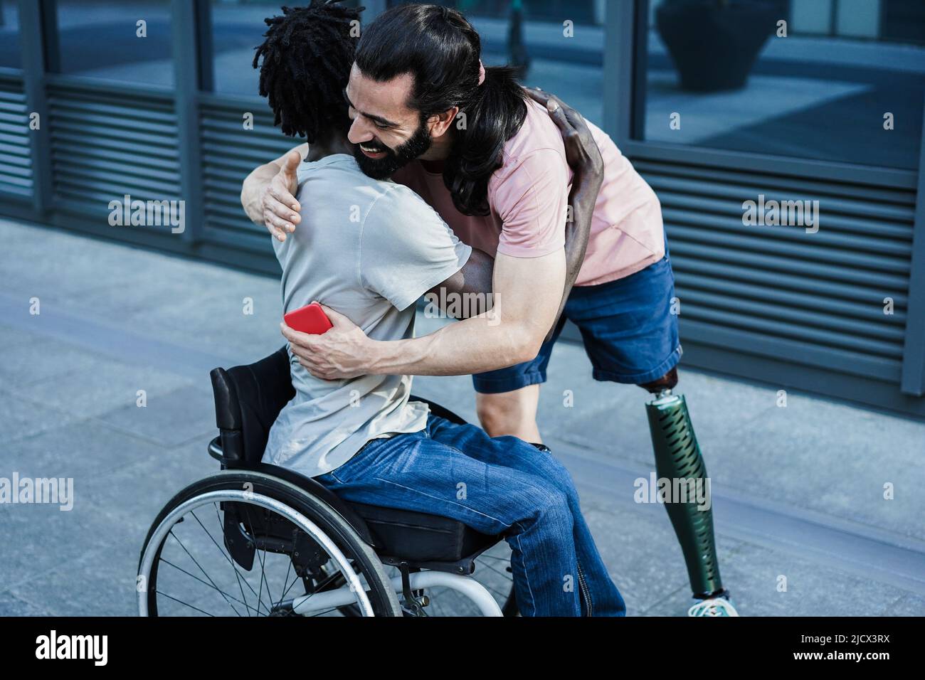 Multiracial friends with disability hugging each other outdoor - Focus ...