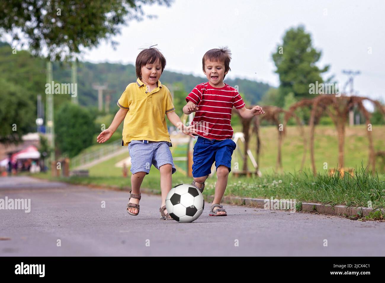 Two cute little kids, playing football together, summertime. Children ...