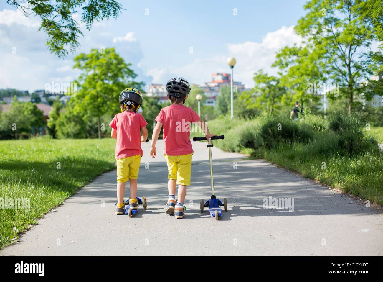 Little children, boy brothers, riding scooters in summer park, kids ...