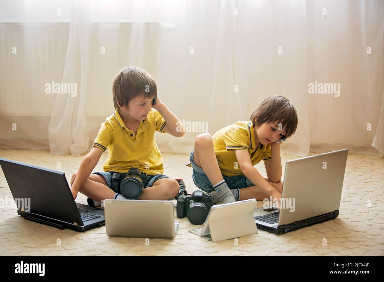 Two boys, preschool children, having fun playing at home with computers ...