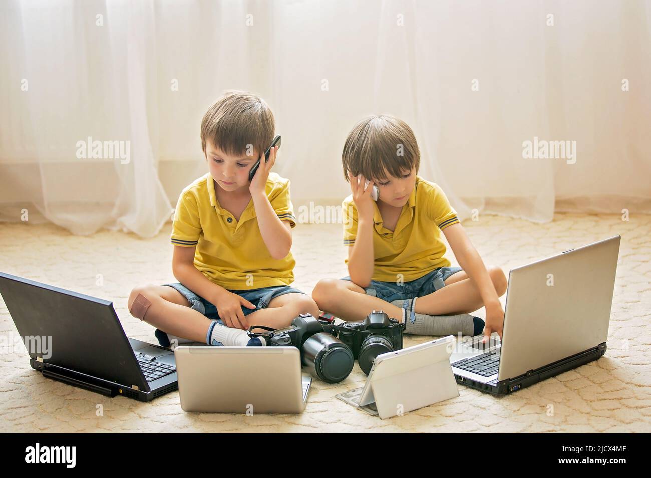 Two boys, preschool children, having fun playing at home with computers ...