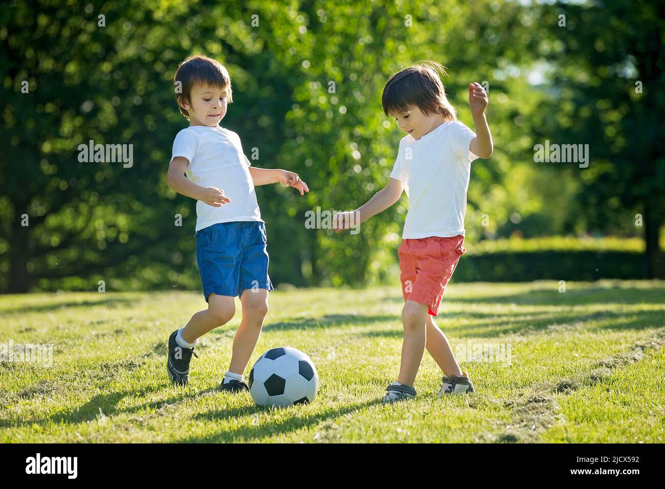 Two cute little kids, playing football together, summertime. Children ...