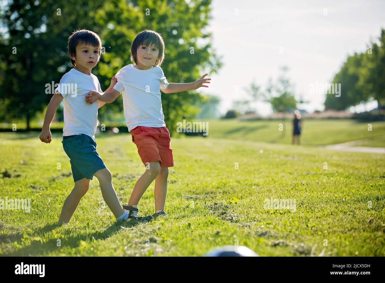 Two cute little kids, playing football together, summertime. Children ...