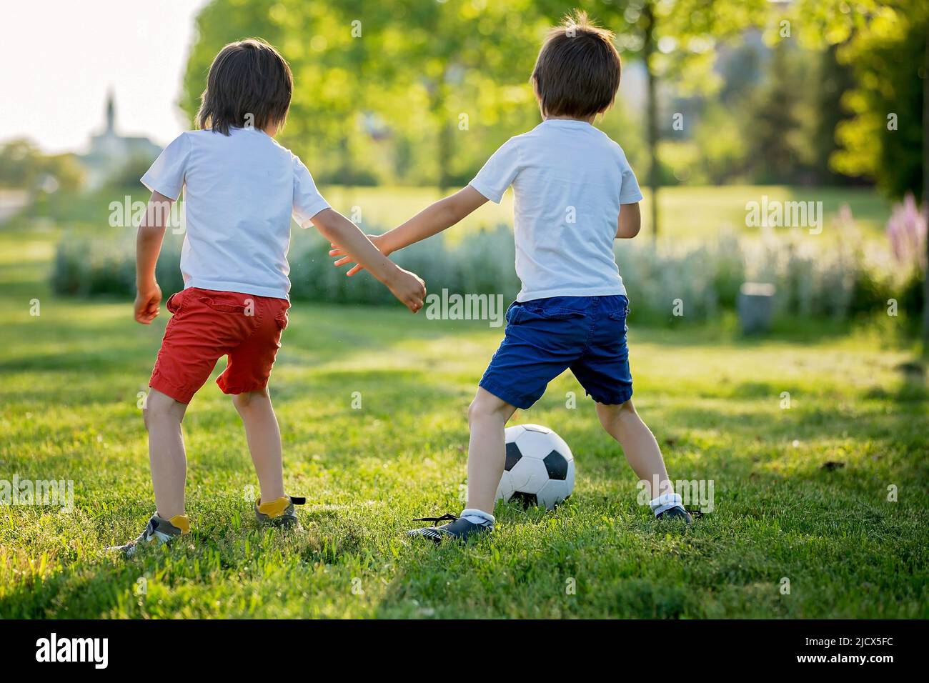 Two cute little kids, playing football together, summertime. Children ...
