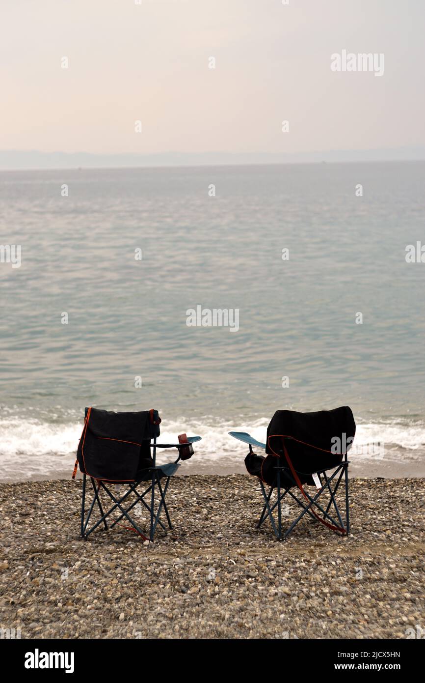 Collapsible beach chairs on pebble stone beach Stock Photo - Alamy