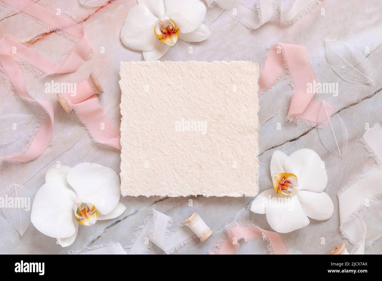 Wedding square card near white orchid flowers and silk ribbons on ...