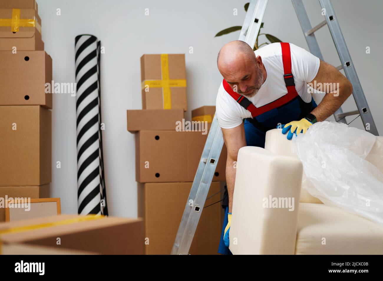 Man mover in uniiform packing sofa for relocation Stock Photo - Alamy