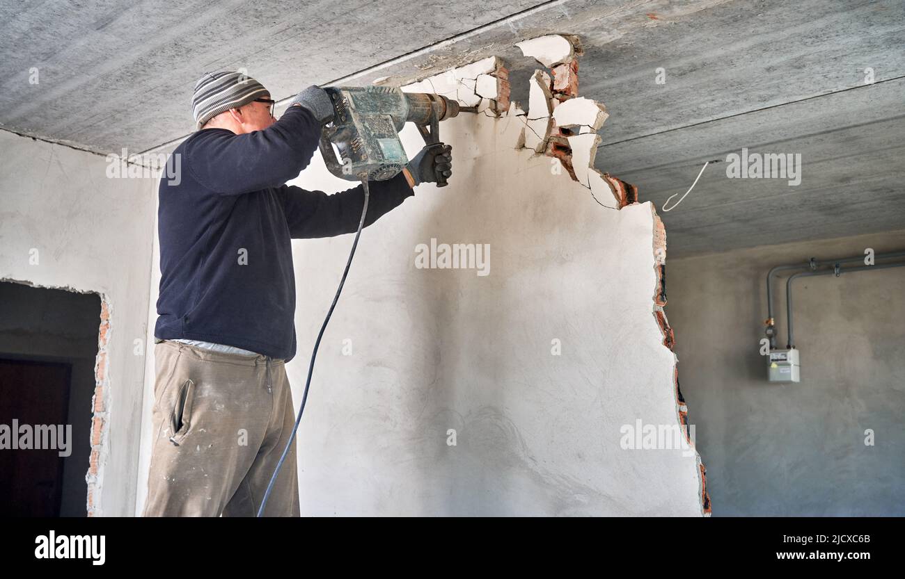 Man builder drilling wall with electric hammer drill. Male worker using ...