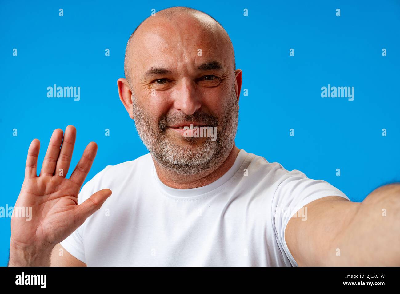 Middle age man wearing casual t-shirt standing over isolated blue ...