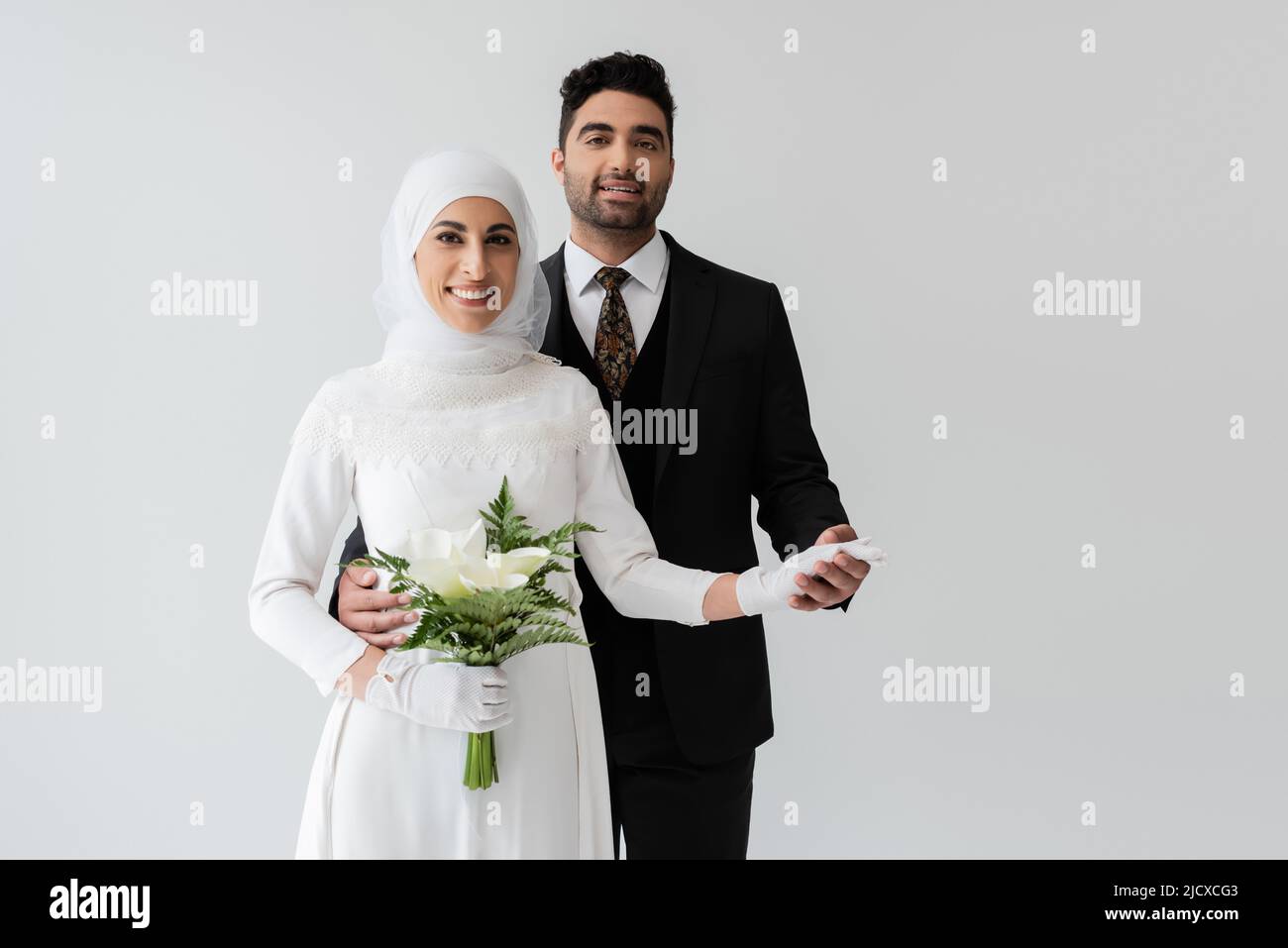 muslim groom holding hand of happy bride in wedding dress with bouquet ...