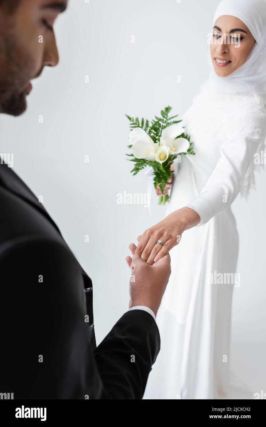happy muslim bride with bouquet holding hands with blurred groom ...