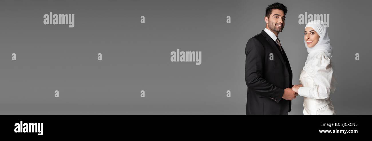 happy muslim bride in wedding dress and groom in suit holding hands ...