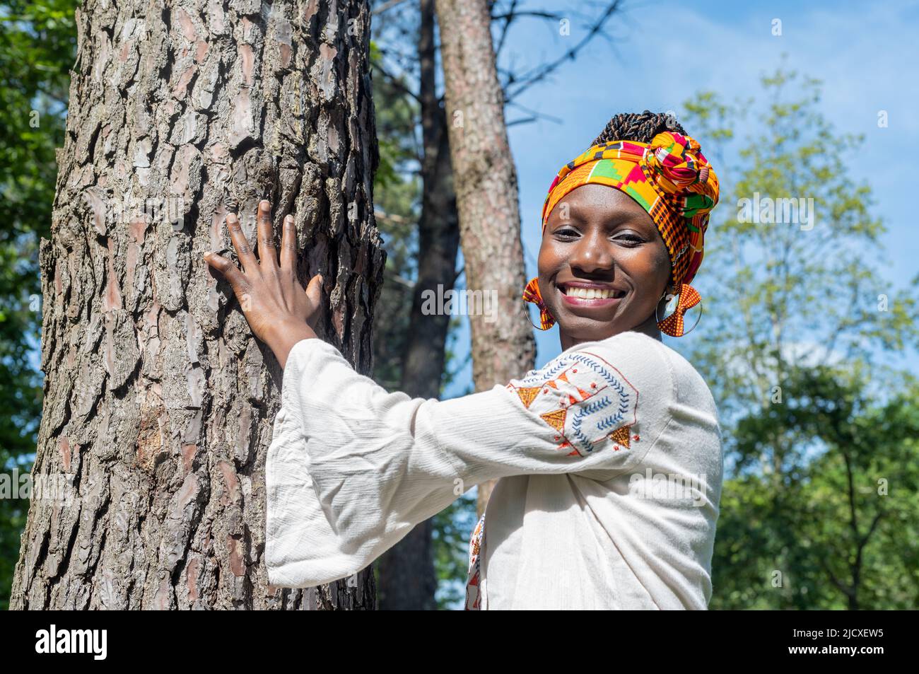 Young woman hugging a tree in the woods while smilling Stock Photo - Alamy