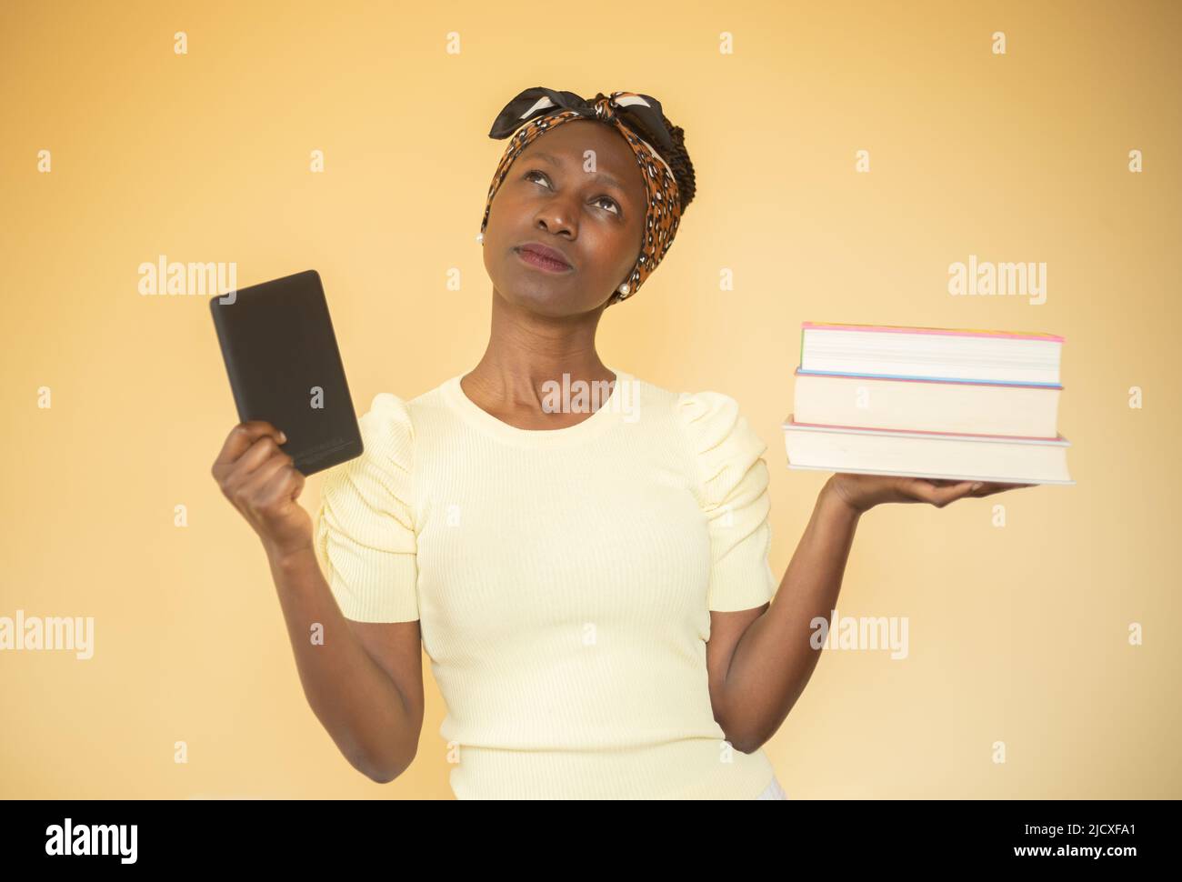 young woman trying to decide between printed books vs e-book Stock ...