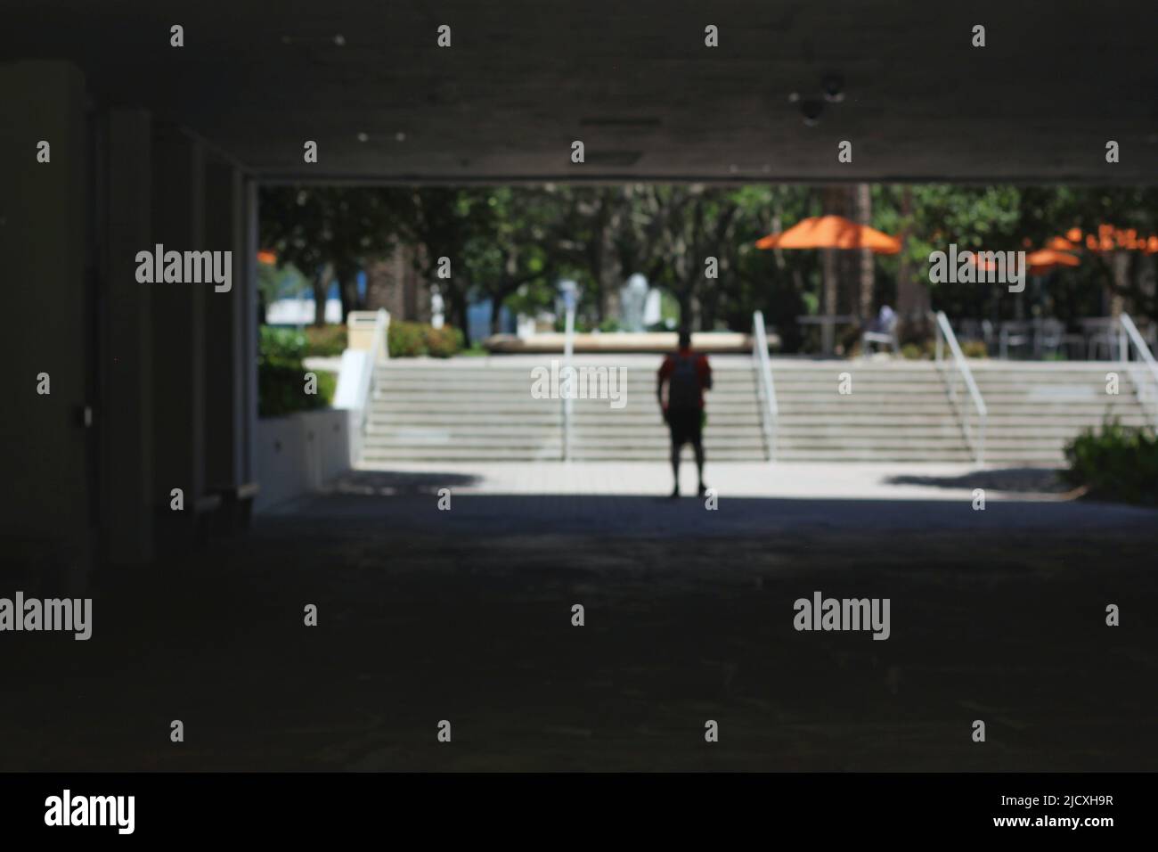 A single person walking thru a simple outdoor hallway towards a set of ...